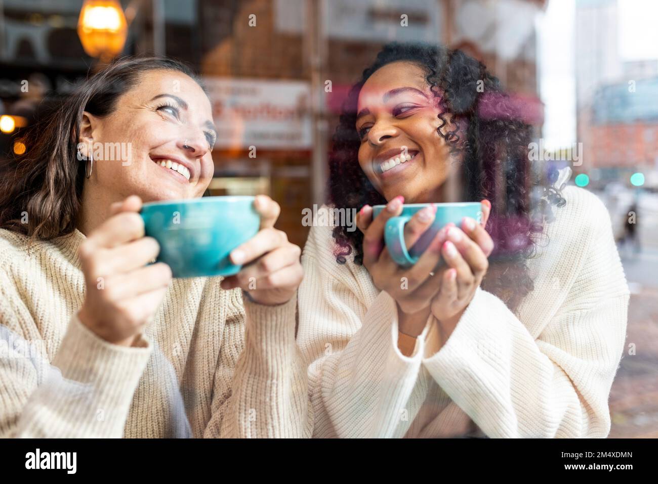 Happy women enjoying coffee in cafe seen through glass Stock Photo - Alamy