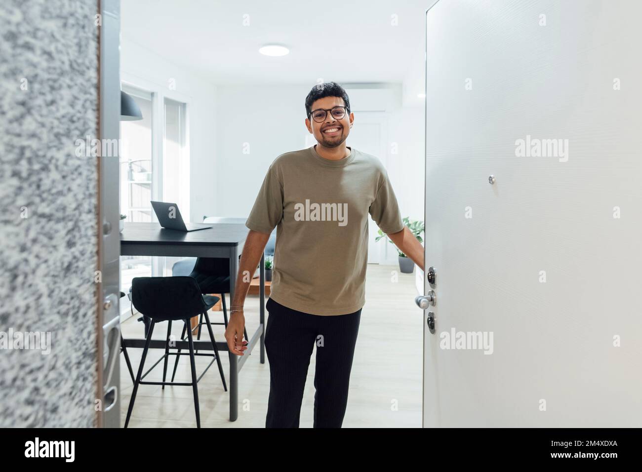 Happy young man opening door at home Stock Photo - Alamy