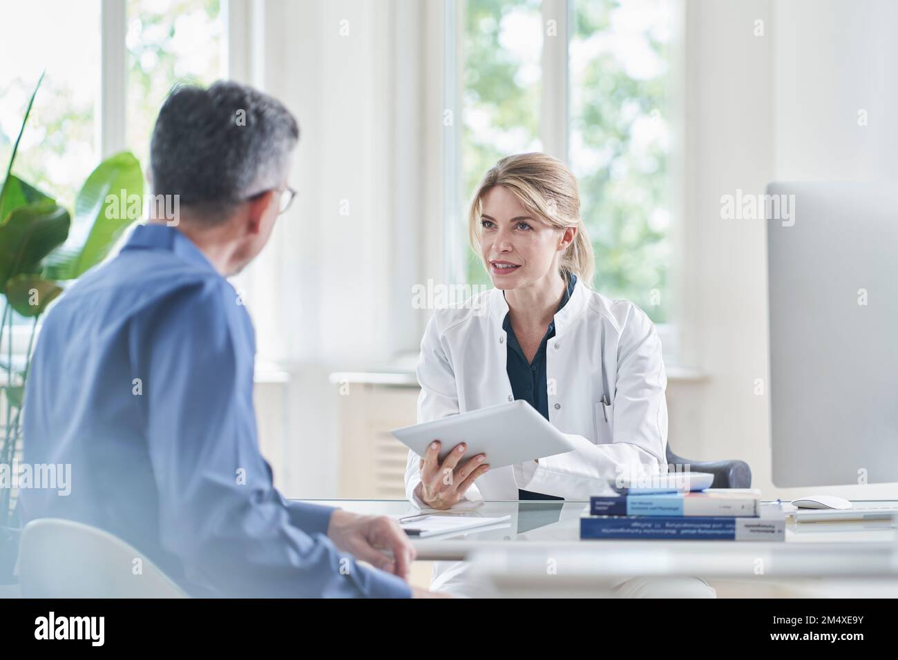 Female doctor giving advice and discussing with patient over tablet PC ...