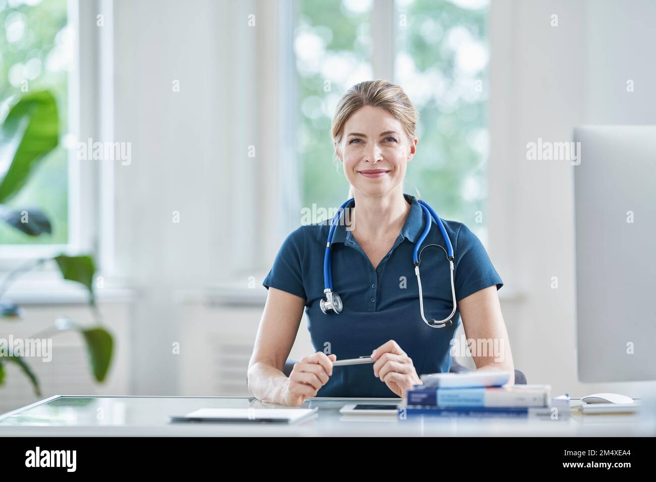Happy doctor sitting table hi-res stock photography and images - Alamy