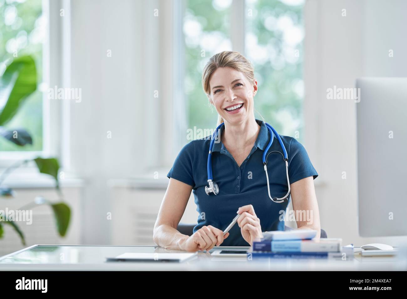 Female doctor laughing at desk in medical practice Stock Photo - Alamy