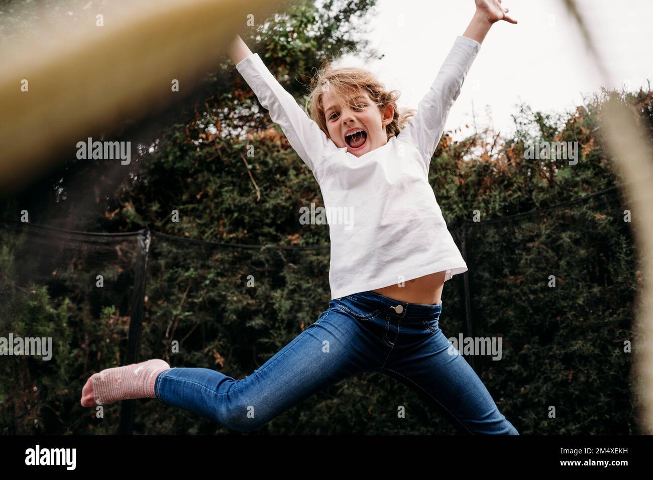 Playful girl with arms raised jumping in garden Stock Photo - Alamy