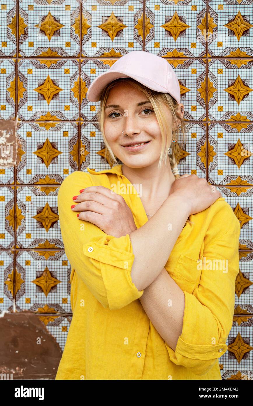 Young woman wearing cap standing in front of patterned wall Stock Photo ...