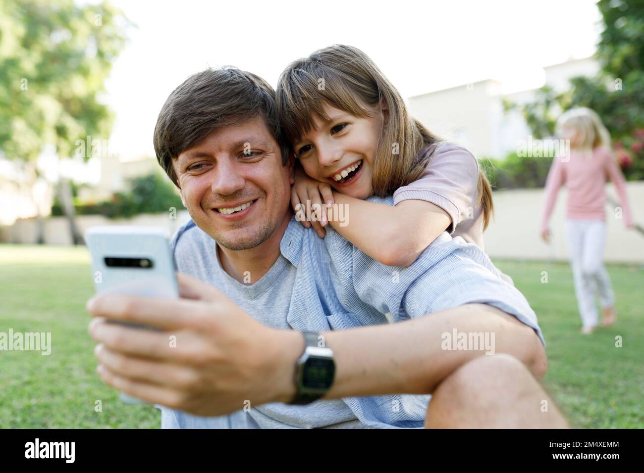 Happy daughter with father using smart phone in park Stock Photo - Alamy