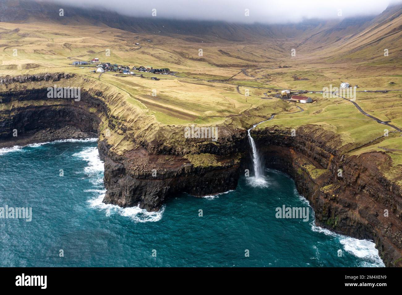 Scenic view of sea and Mulafossur waterfall under cloudy sky Stock ...