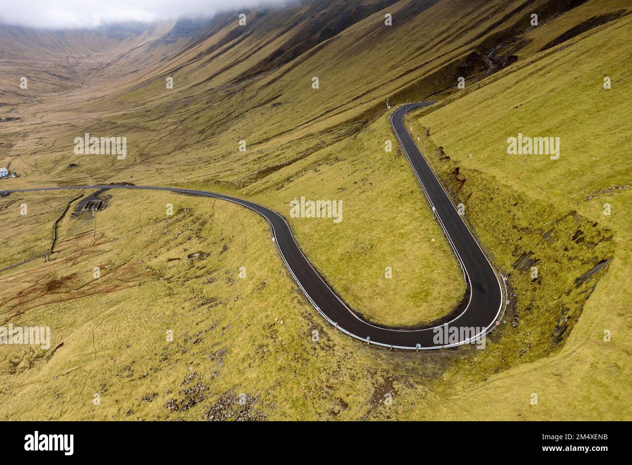 Curved empty road in valley by mountain Stock Photo - Alamy