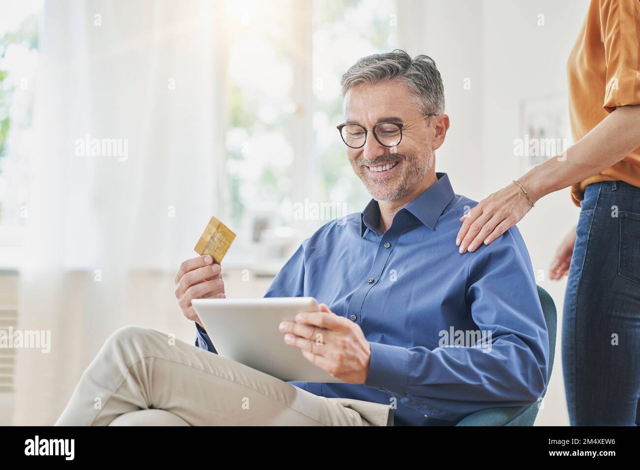 Happy man holding credit card doing online shopping over tablet PC with ...