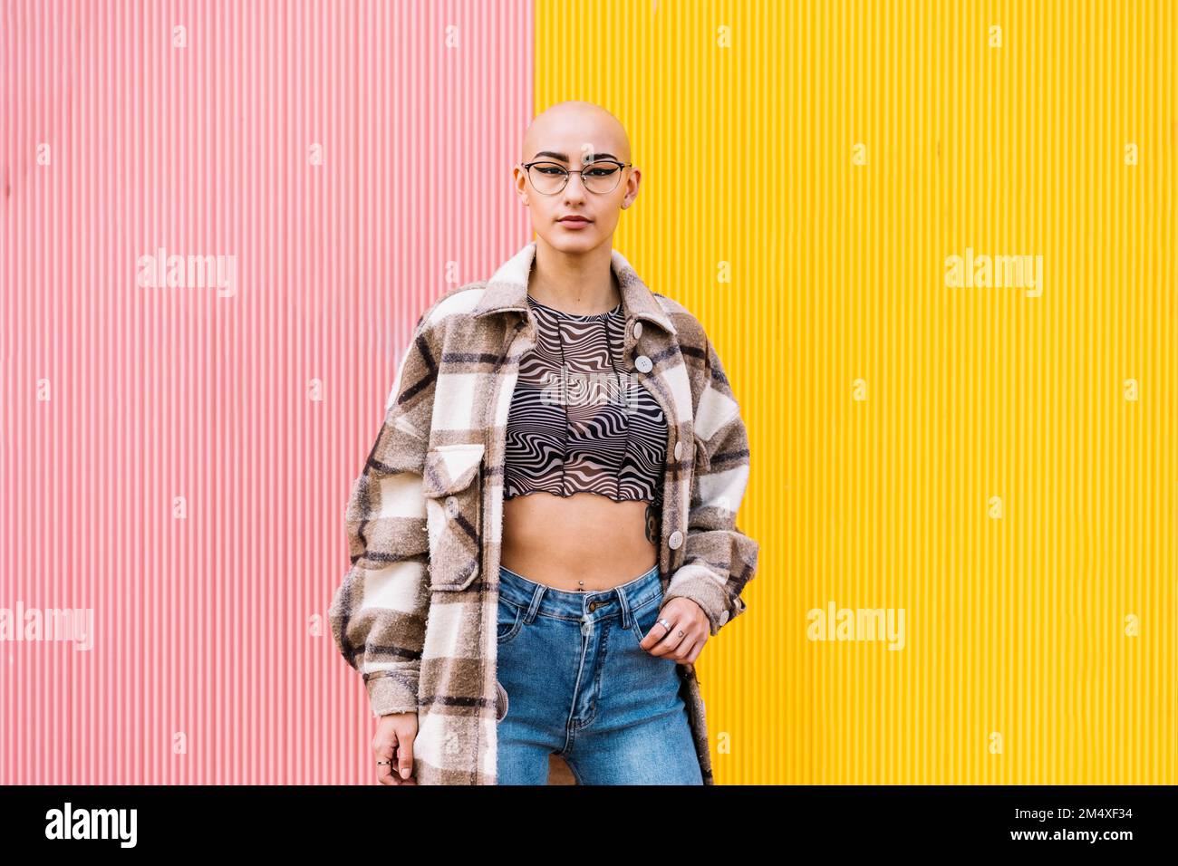 Young woman wearing plaid jacket standing in front of colored wall ...