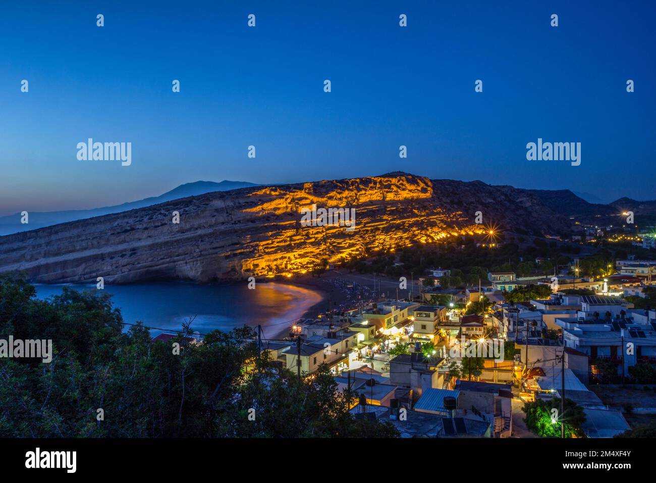 Greece, Crete, Matala, View of illuminated coastal village at night ...