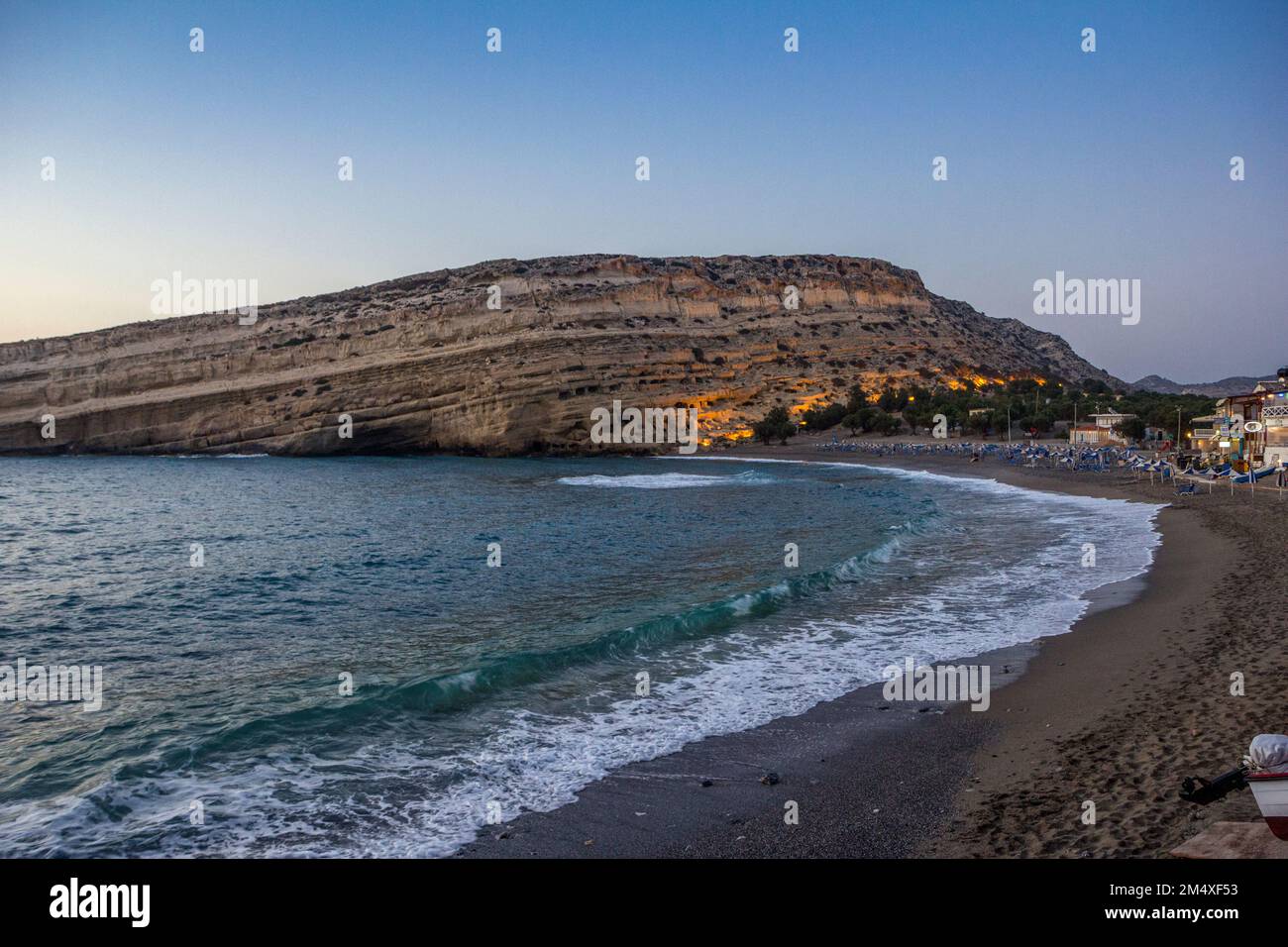 Greece, Crete, Matala, Matala Beach and cliffside caves at dusk Stock ...