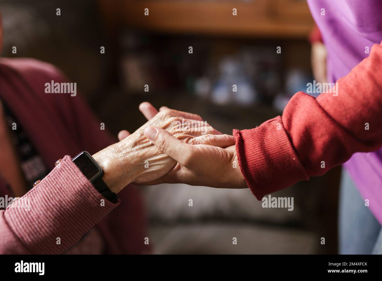 Caregiver holding senior woman's hand at home Stock Photo - Alamy