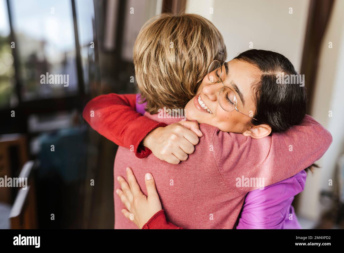 Happy young caregiver hugging senior woman at home Stock Photo - Alamy
