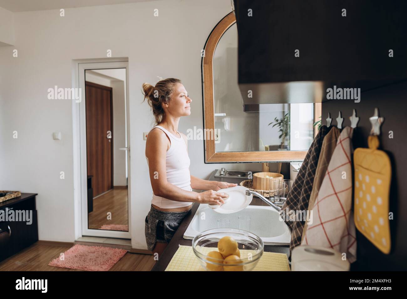 Woman washing dishes in the kitchen looking out of window Stock Photo ...