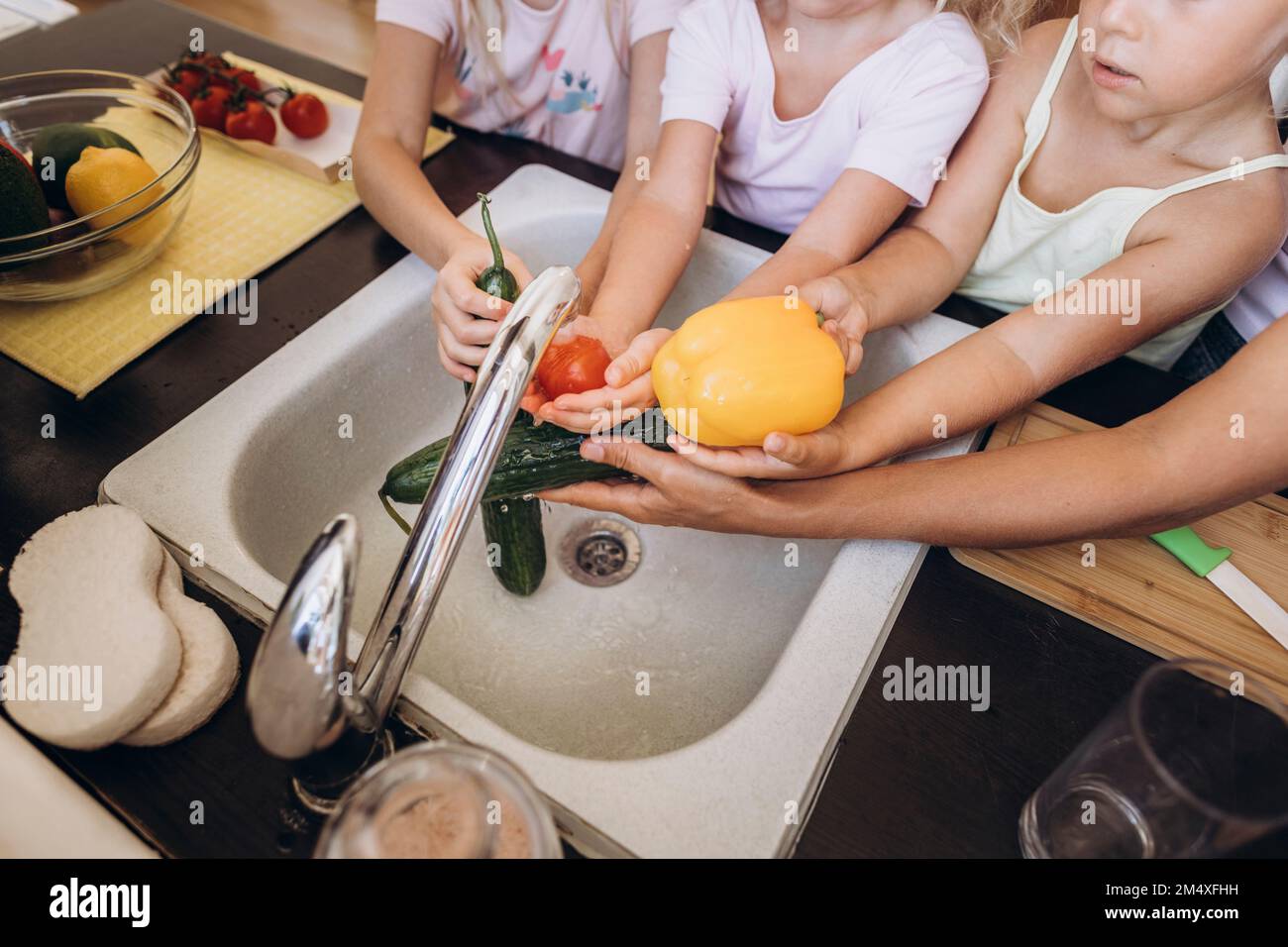 Mother and daughters washing vegetables in the kitchen Stock Photo - Alamy