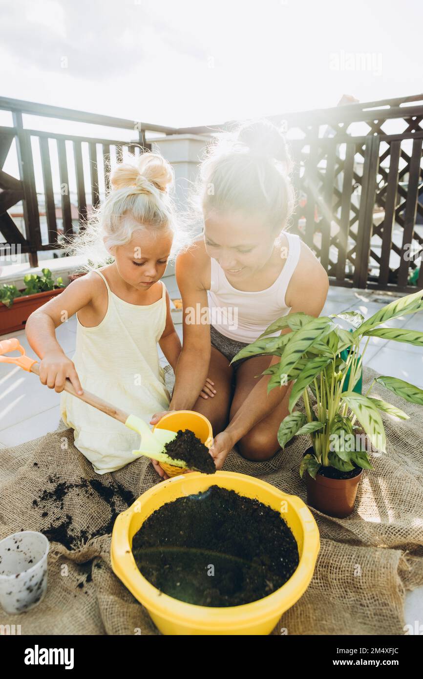 Mother and daughter planting on roof terrace together Stock Photo - Alamy
