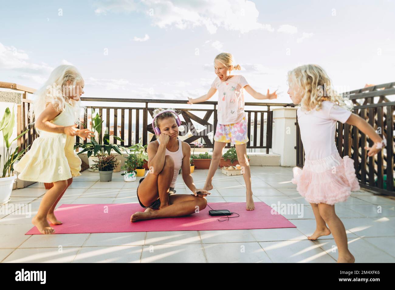 Girls romping around annoyed mother on roof terrace Stock Photo - Alamy