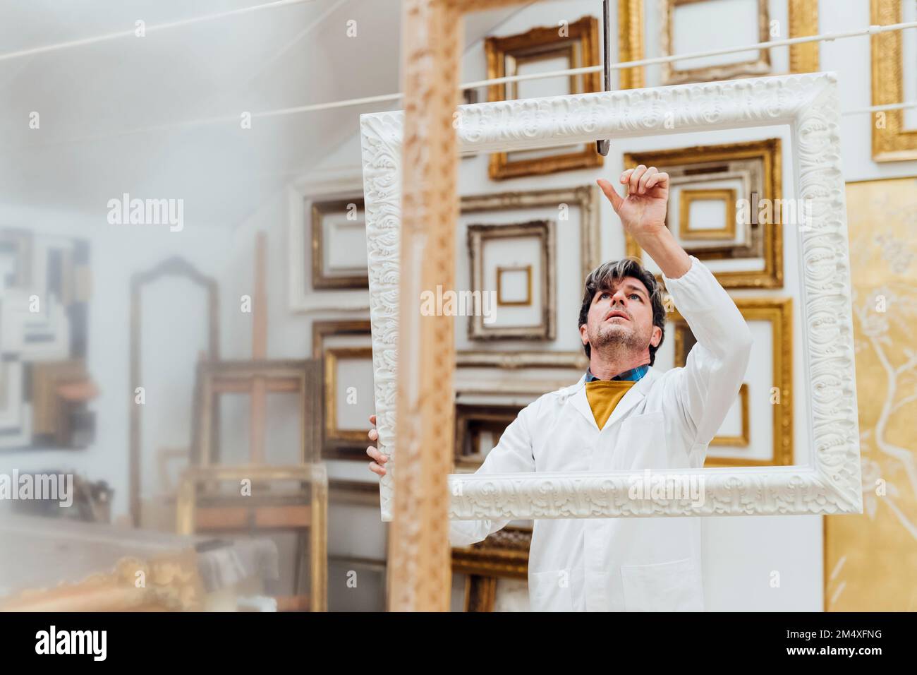 Carpenter examining frames in woodshop Stock Photo - Alamy
