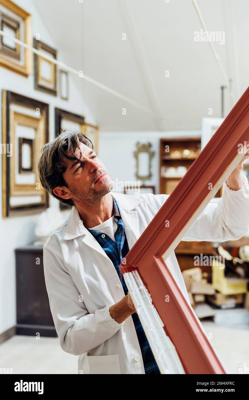 Craftsman examining wooden frame in workshop Stock Photo - Alamy