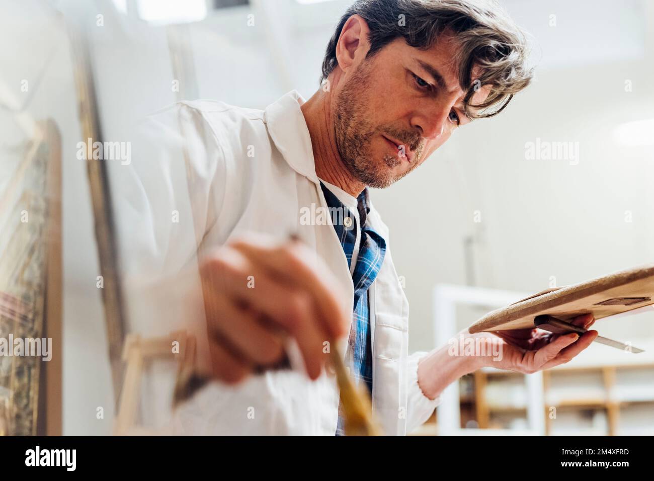 Craftsman wearing lab coat working in workshop Stock Photo - Alamy