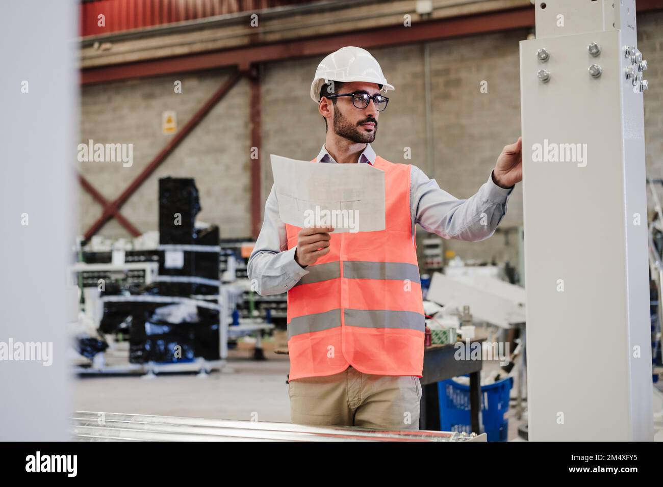 Engineer with blueprint operating machinery at industry Stock Photo - Alamy