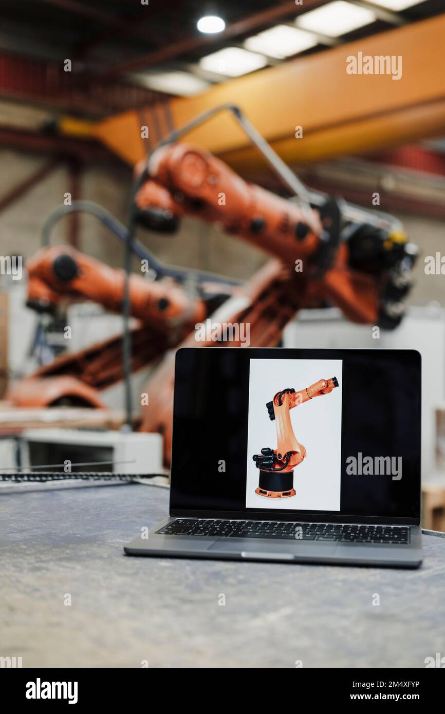 Laptop with robotic arm picture at desk in industry Stock Photo - Alamy