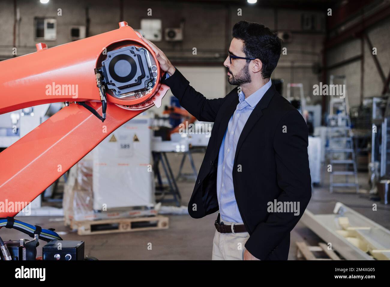 Engineer examining robotic arm in factory Stock Photo - Alamy
