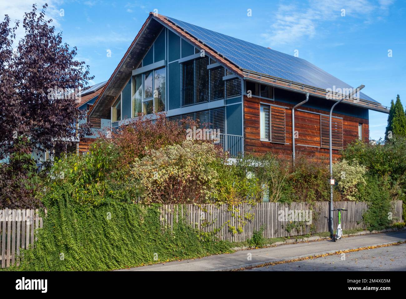 Germany, Bavaria, Munich, Overgrown fence surrounding modern passive ...