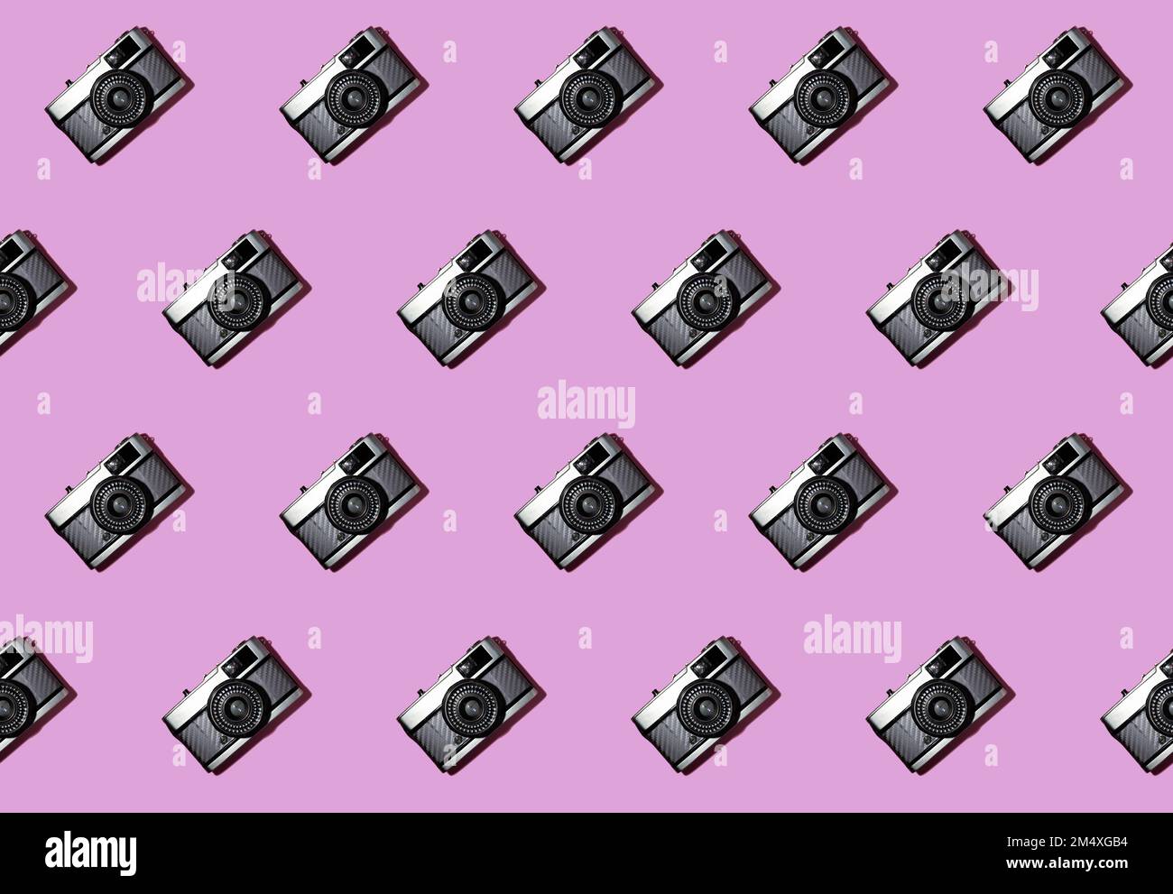 Three dimensional pattern of rows of cameras against pink background ...