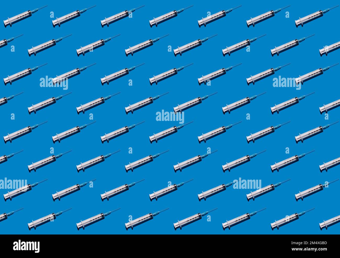 Pattern of rows of syringes flat laid against blue background Stock ...
