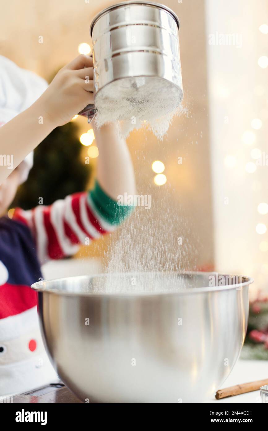 Hands of boy sieving flour for gingerbread at kitchen counter Stock ...