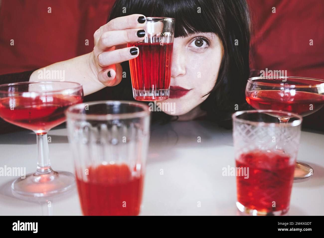 Woman covering eye from glass of red alcoholic drink Stock Photo - Alamy