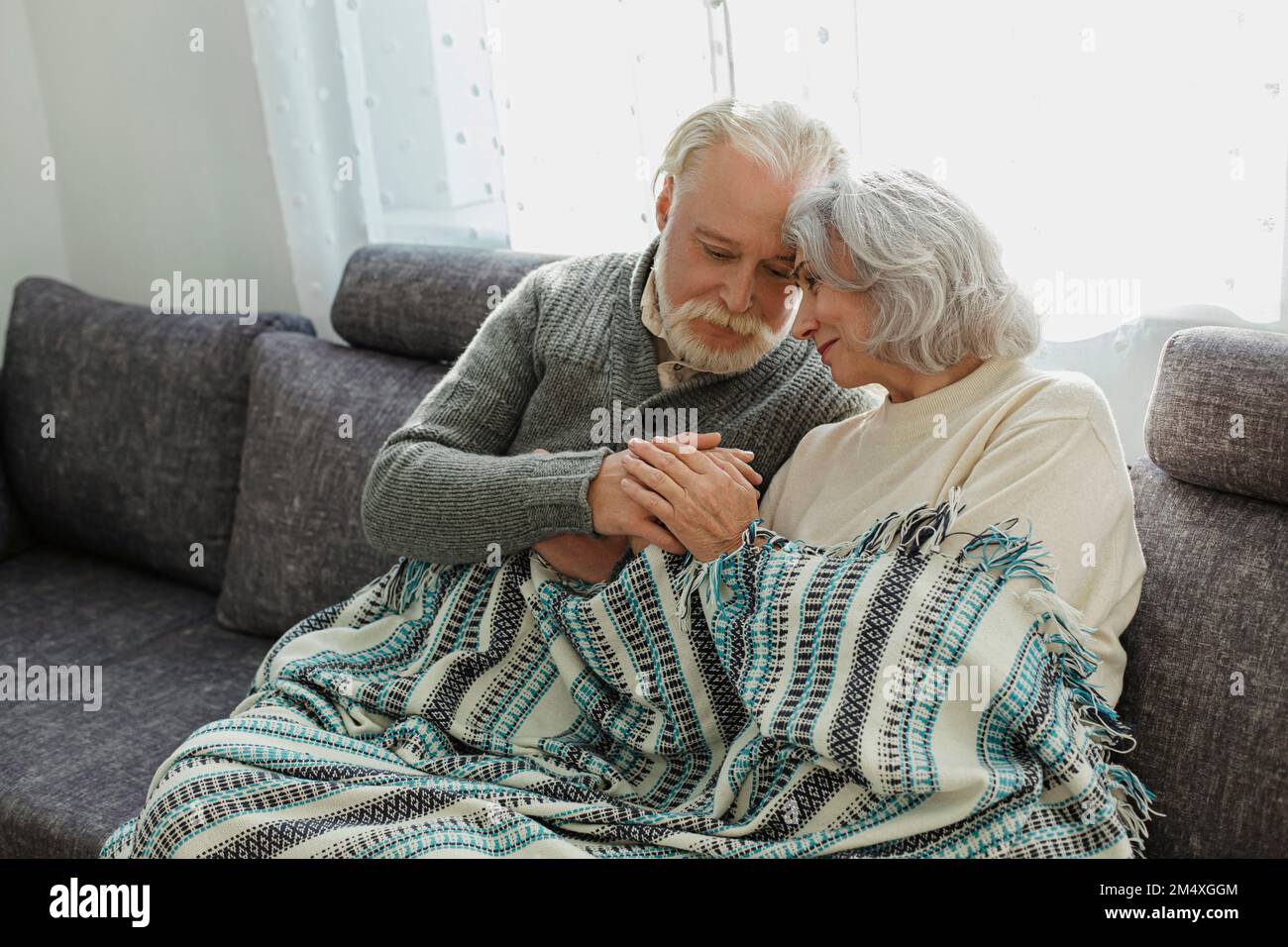 Senior couple cuddling on the couch under a blanket Stock Photo - Alamy