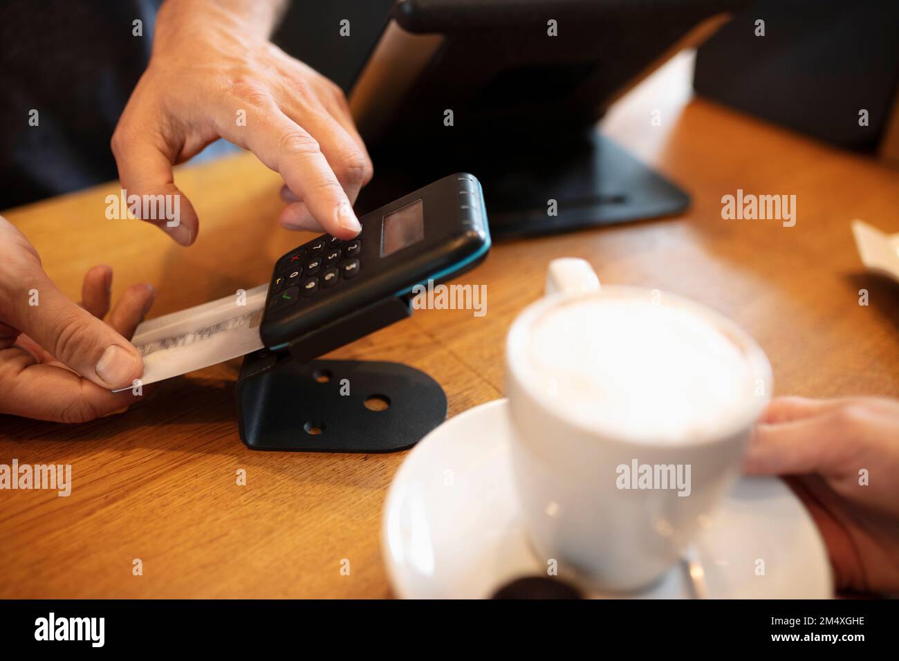 Hands of cashier using card machine at cafe counter Stock Photo - Alamy