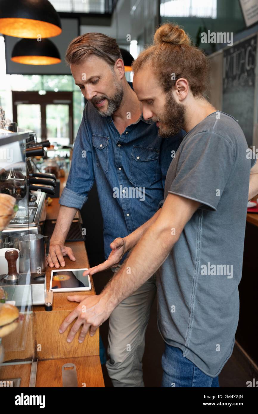 Coffee shop owner sharing tablet PC with barista in cafe Stock Photo ...