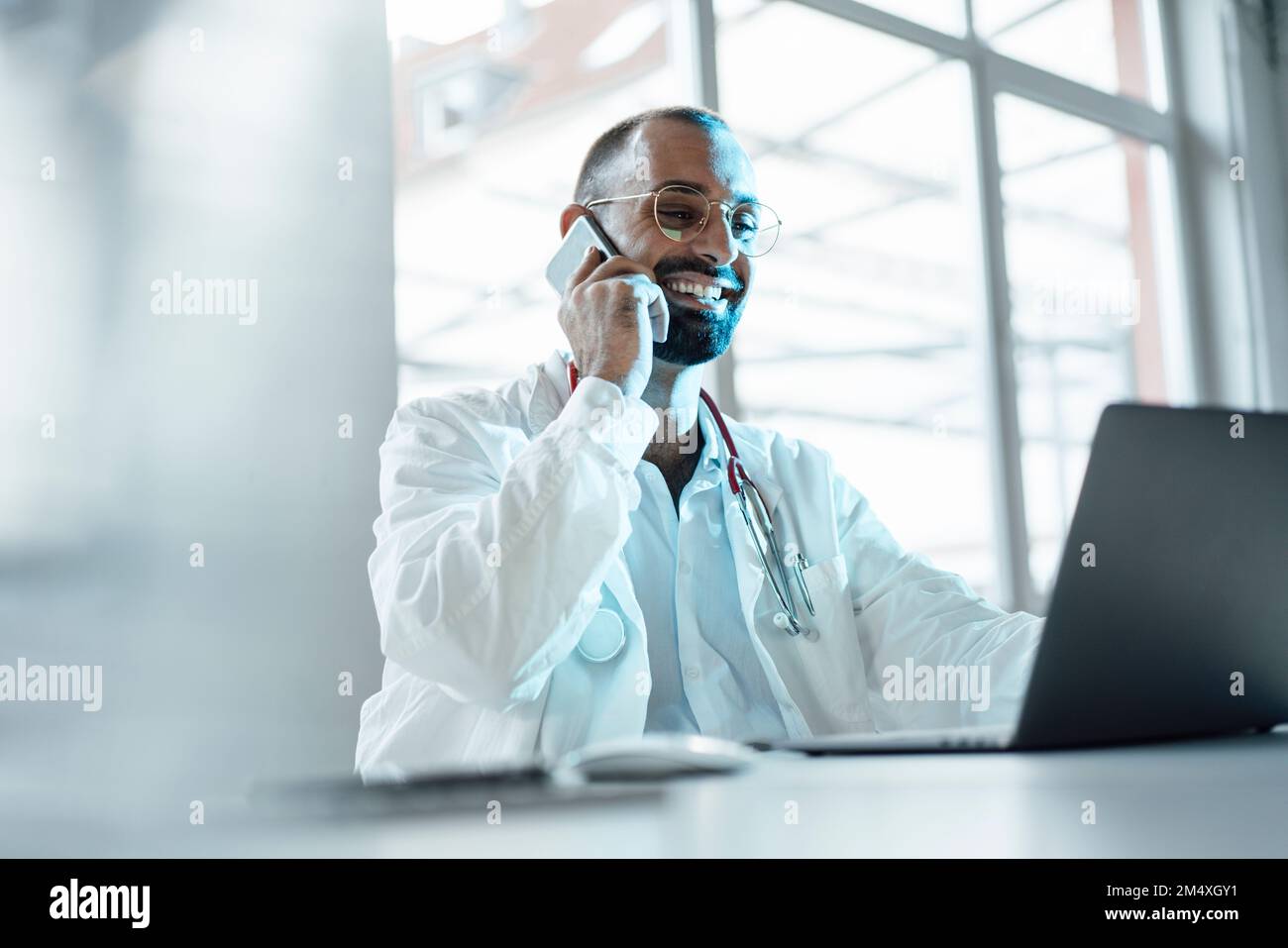 Happy doctor sitting table hi-res stock photography and images - Alamy