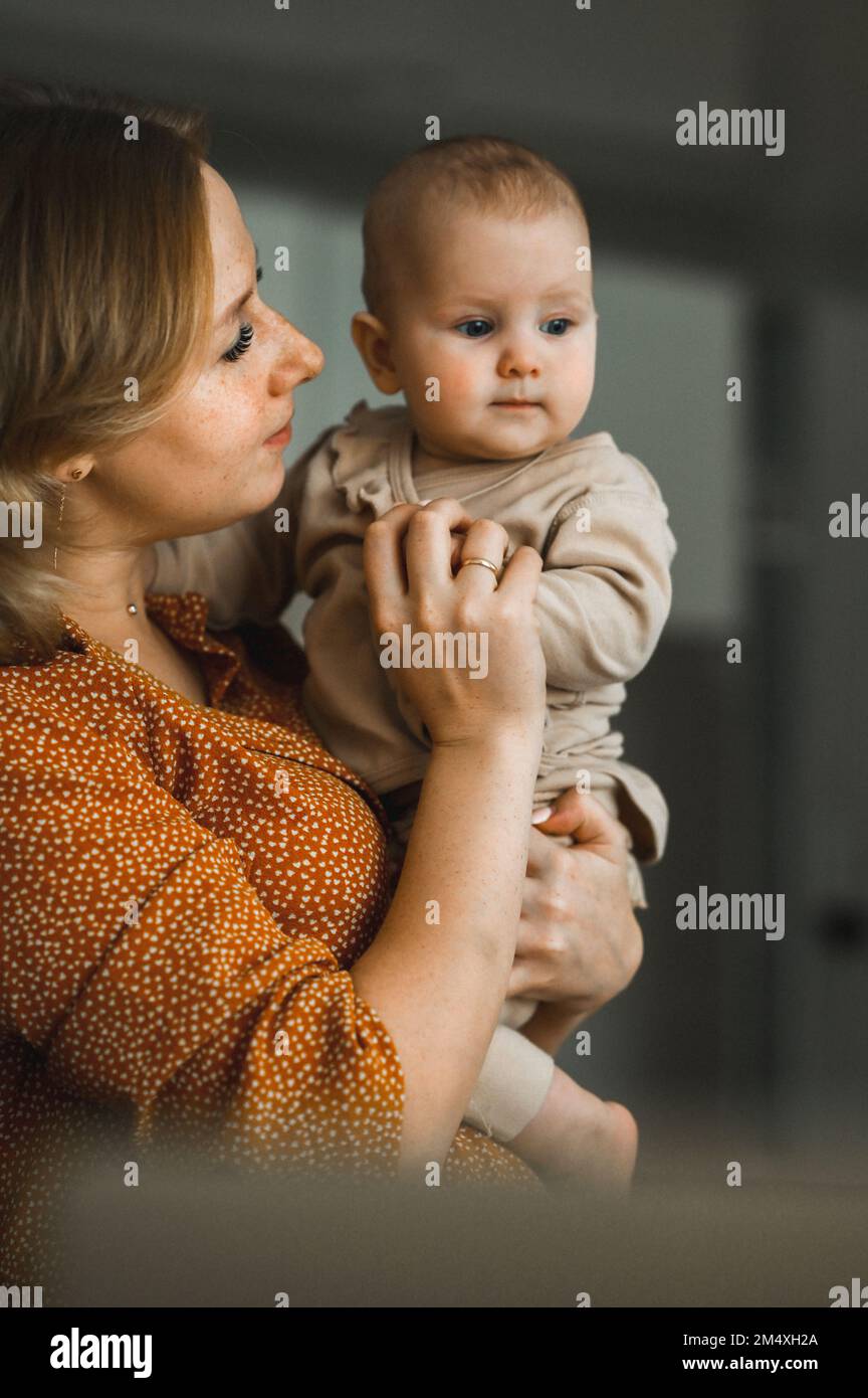 Mother embracing baby daughter at home Stock Photo - Alamy