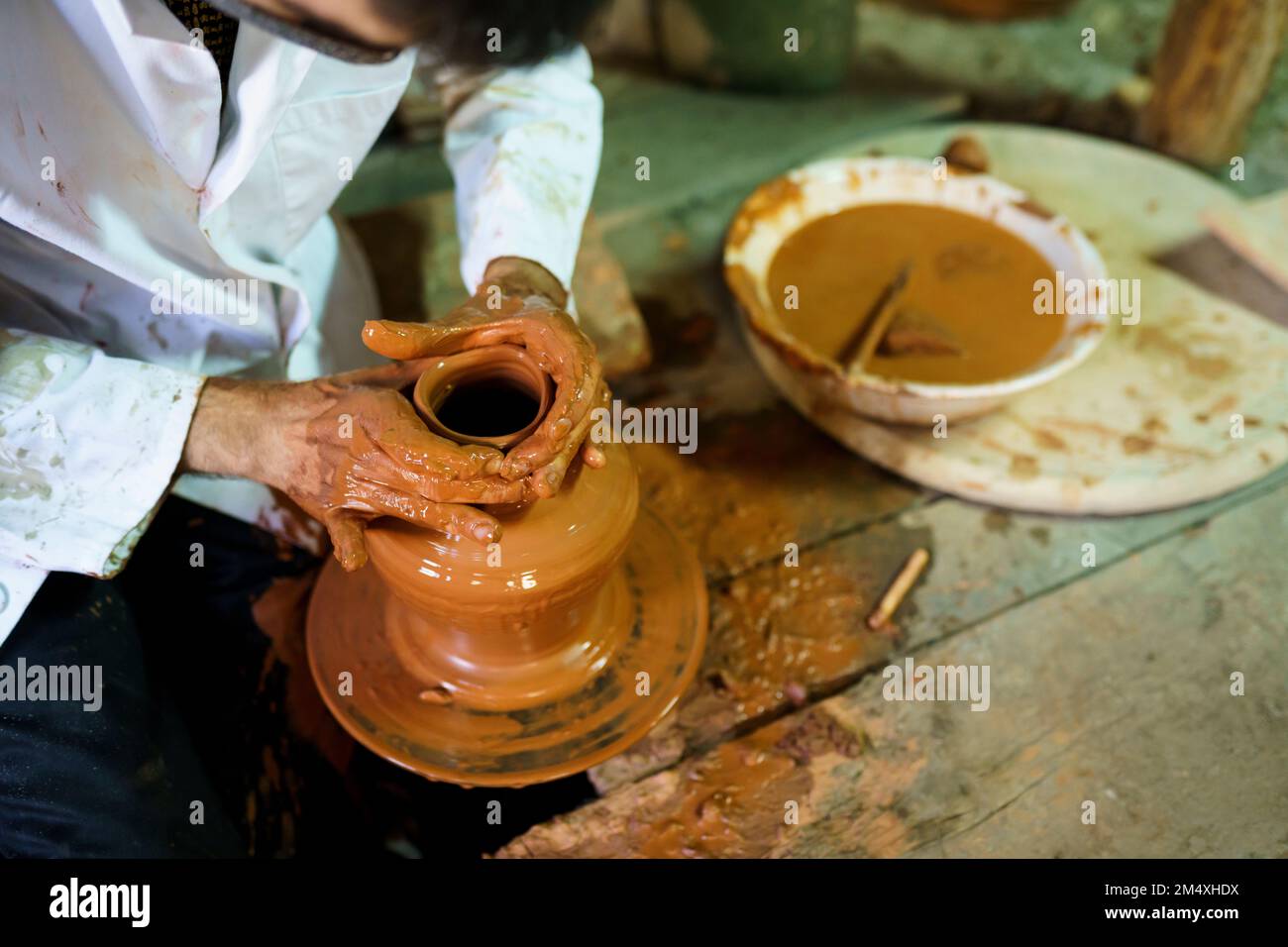 Craftsman molding pot on pottery wheel in factory Stock Photo - Alamy