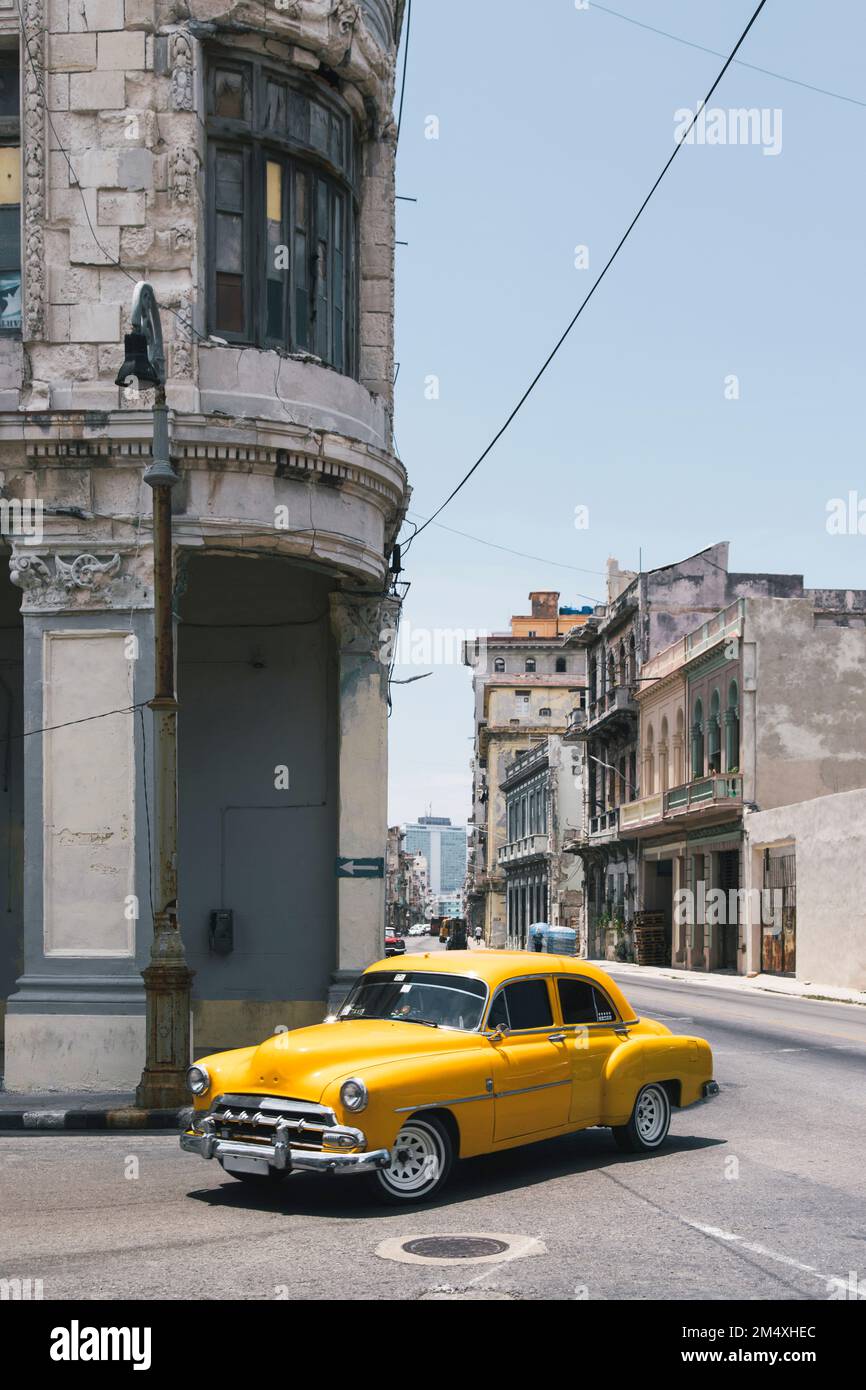 Cuba, Havana, Yellow vintage car driving along street in Centro Habana ...