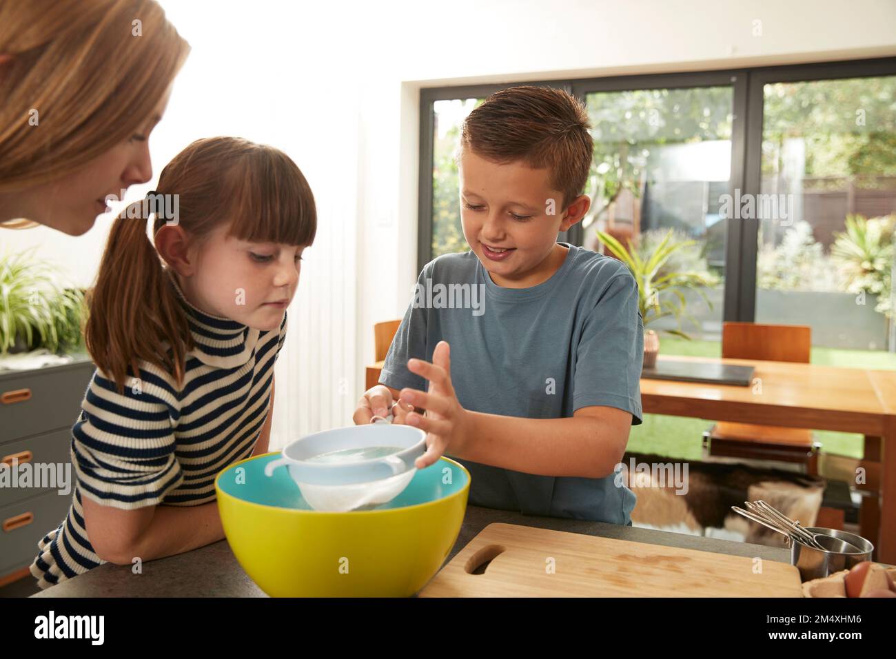 Smiling boy sieving flour by sisters at home Stock Photo - Alamy