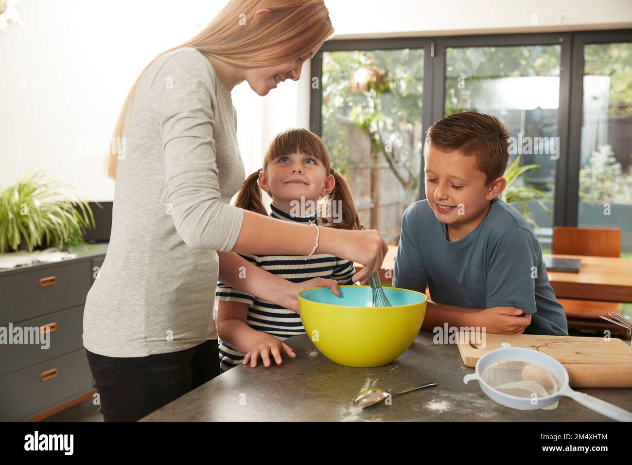 Girl and brother helping sister in preparing cookies at home Stock Photo - Alamy