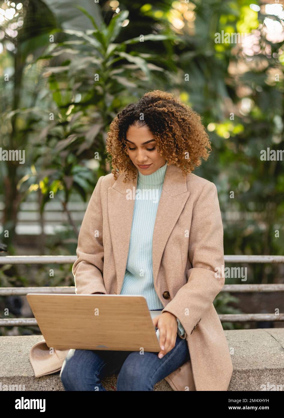 Young businesswoman using laptop on bench Stock Photo - Alamy