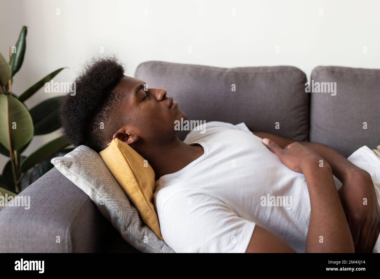 Young man sleeping on sofa at home Stock Photo - Alamy