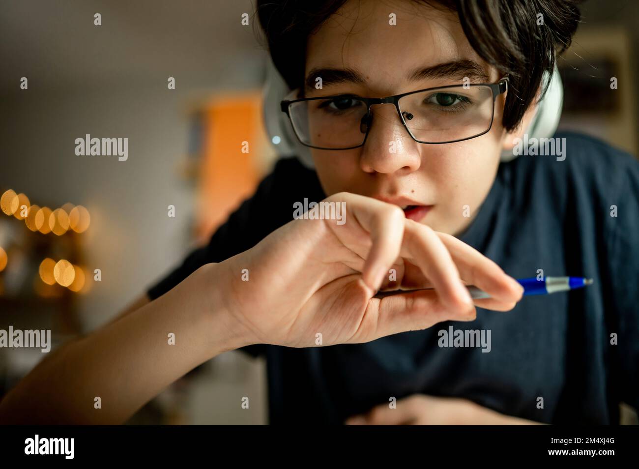Boy wearing eyeglasses holding pen at home Stock Photo - Alamy