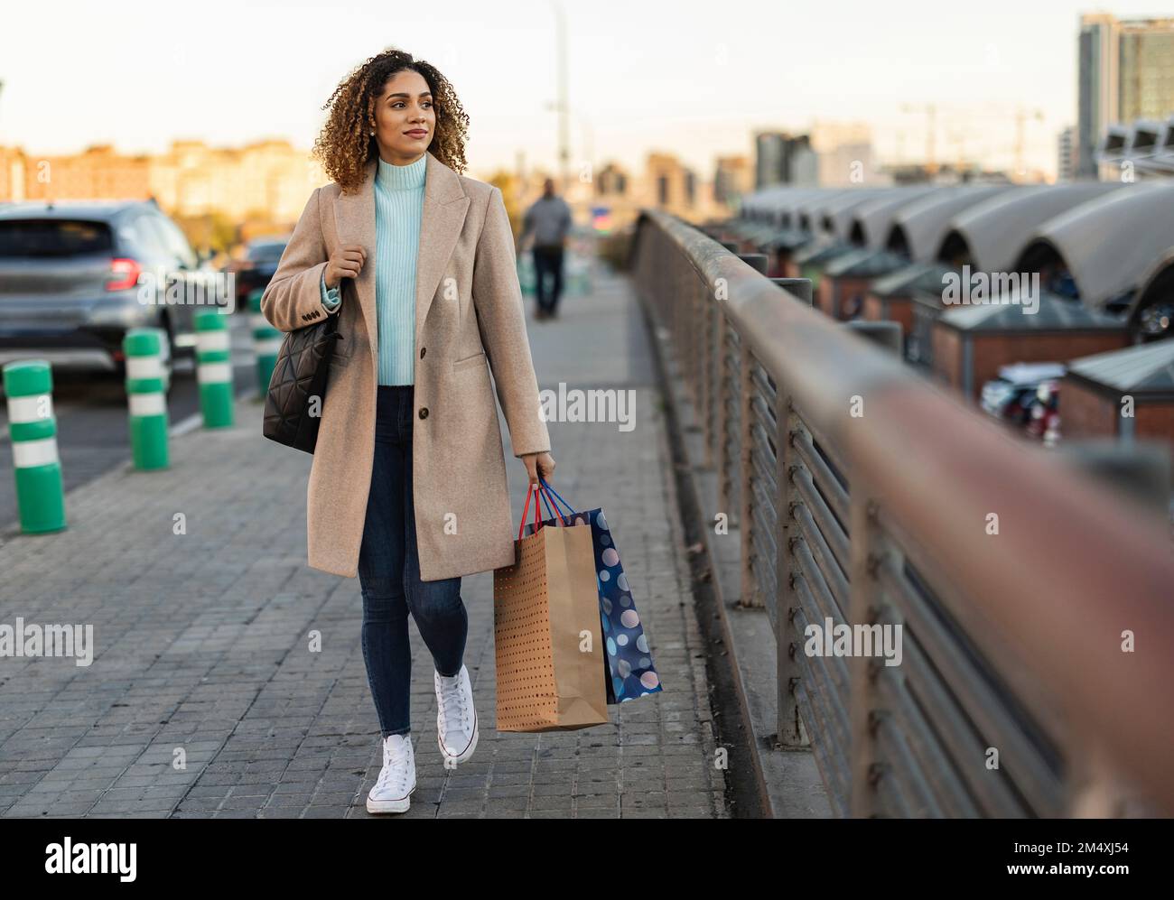 Beautiful young woman holding shopping bags walking on footpath Stock ...