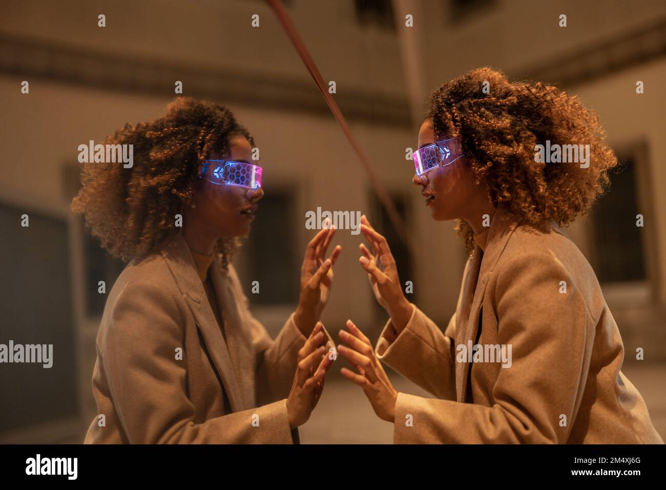 Woman wearing smart glasses looking and touching her reflection on ...