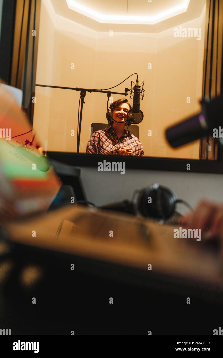 Happy singer recording music through microphone in studio Stock Photo ...