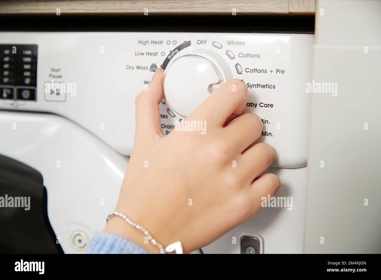 Hand of girl adjusting knob on washing machine Stock Photo - Alamy