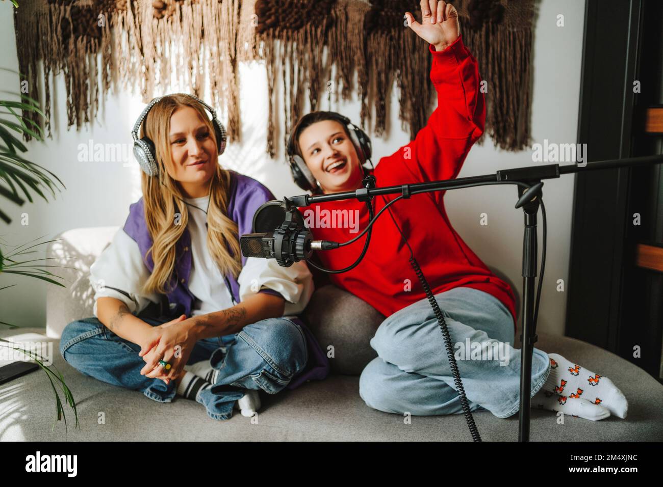 Happy musician with colleague wearing headphones in front of microphone ...