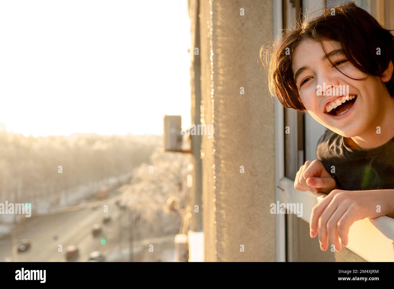 Happy boy looking out through window at home Stock Photo - Alamy