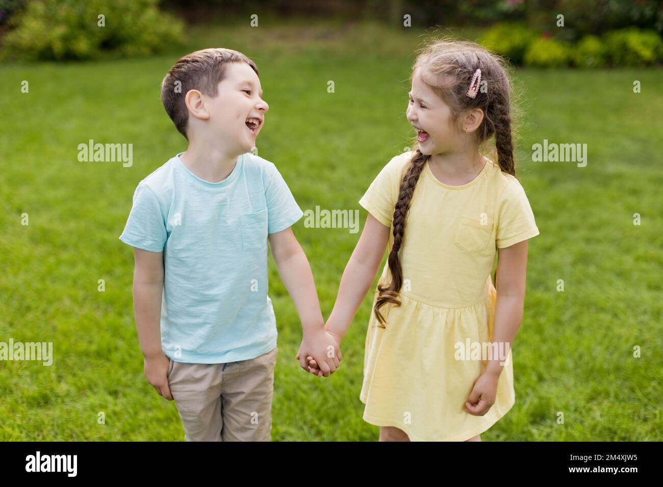 Brother and sister holding hands and laughing together in back yard ...